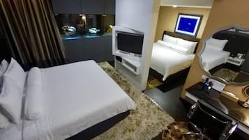 Quarto de hotel com uma cama grande, televisão, secretária pequena e espelho.