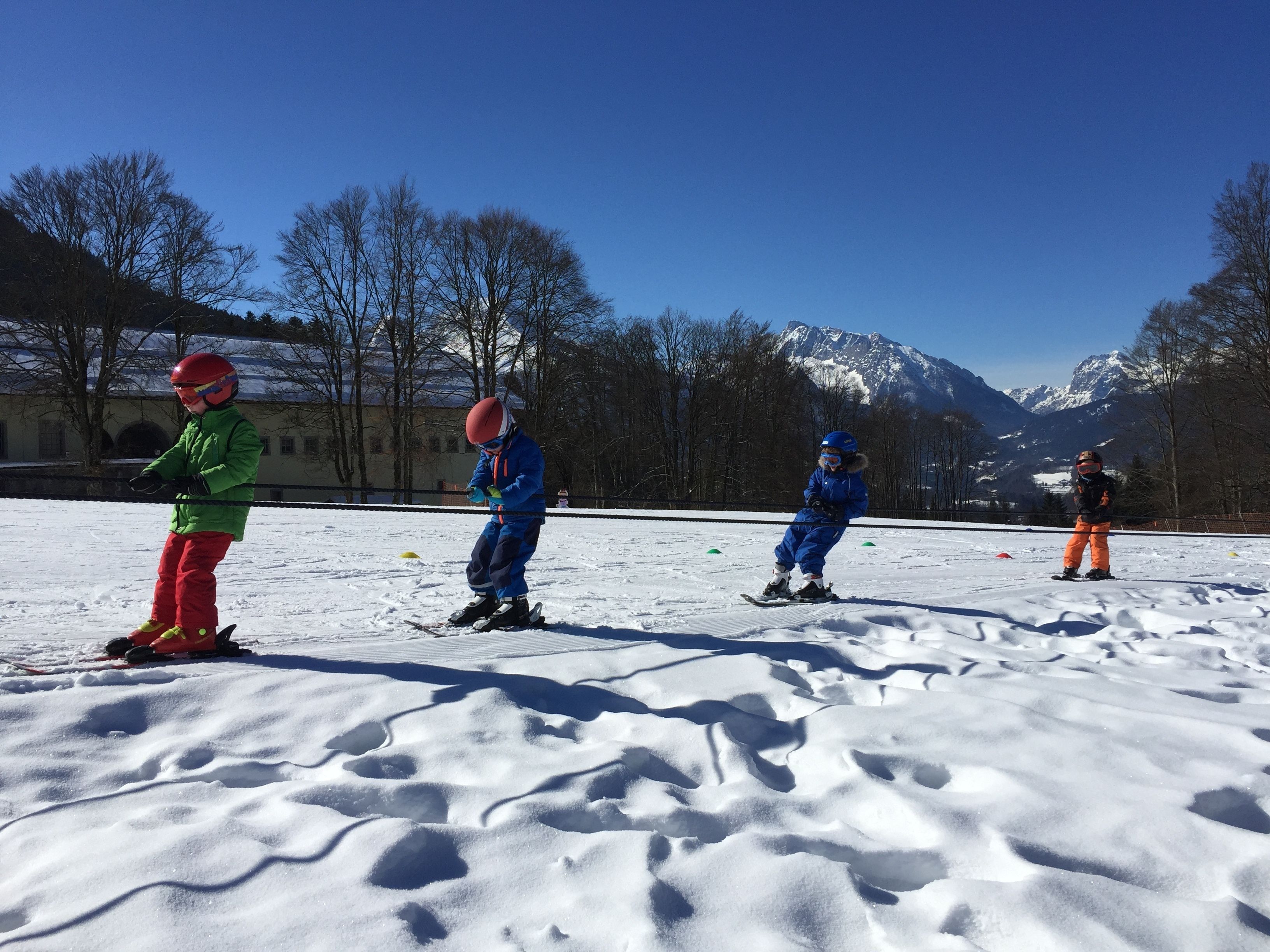 Uma área externa coberta de neve com três crianças esquiando.