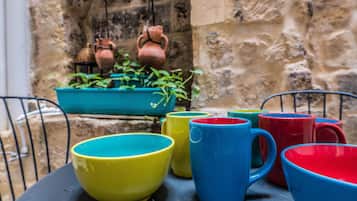 Uma mesa com canecas e tigelas de cerâmica coloridas, um suporte para panelas pendurado e uma planta em vaso.