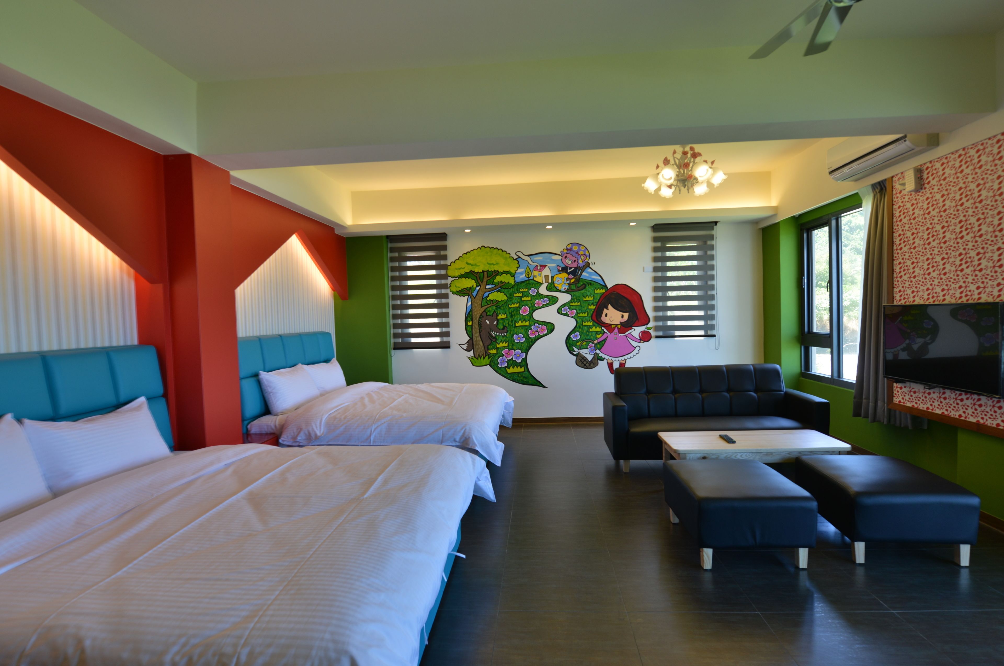 Quarto de hotel com duas camas, um sofá, uma televisão e um mural na parede.