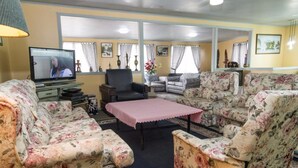 Uma sala de estar com sofás de padrão floral, uma televisão e uma mesa rosa.