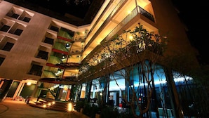 Um hotel de vários andares com design moderno, com varandas e um átrio central com plantas.