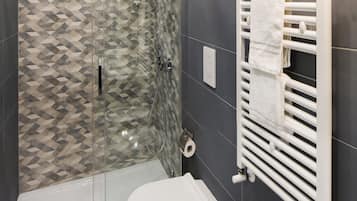 Um banheiro moderno com box de vidro, vaso sanitário e pia.