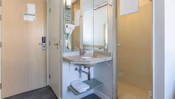 Casa de banho moderna com lavatório de granito, secador de cabelo manual e cabine de duche em vidro.