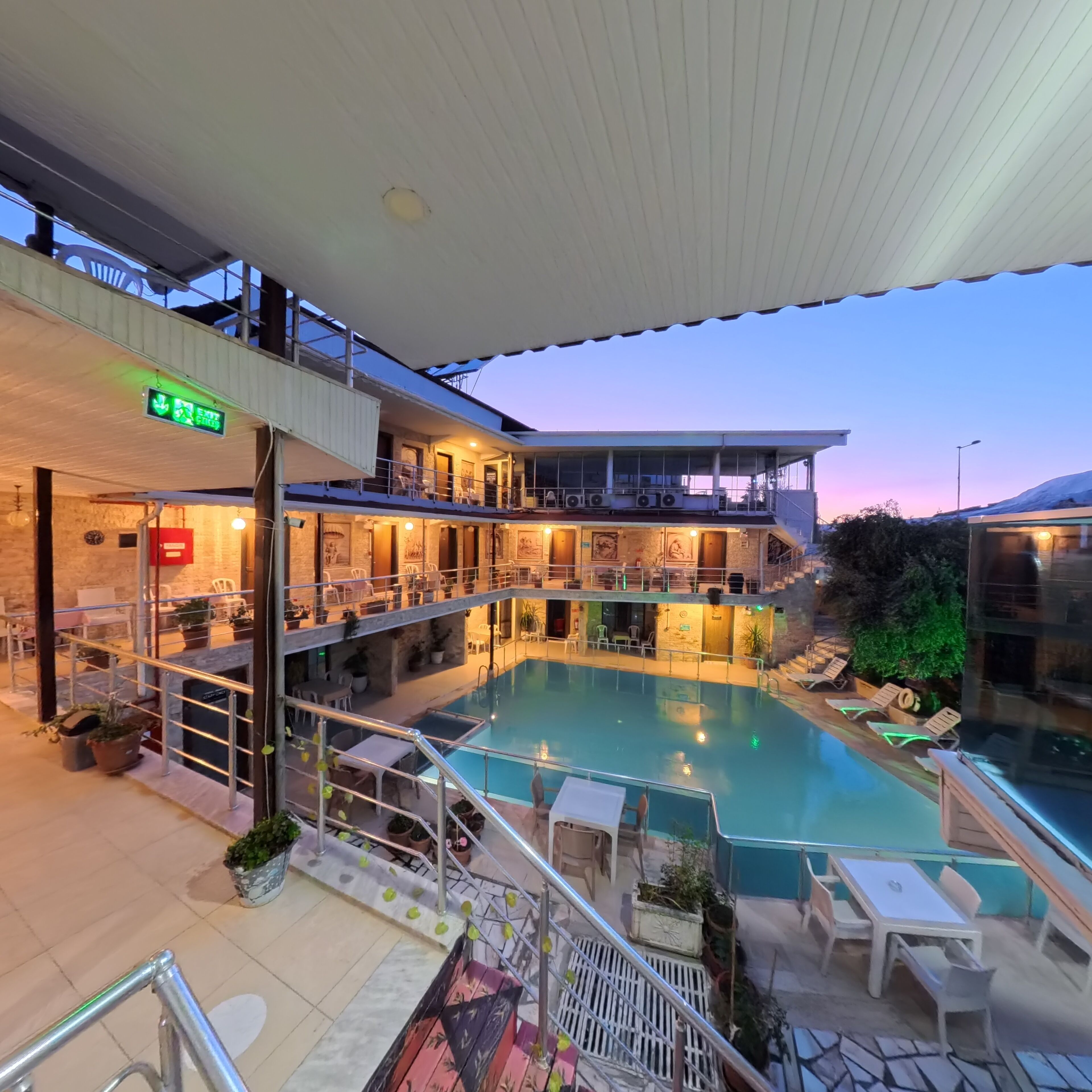 Um hotel com vários níveis, piscina, área de estar ao ar livre e escadaria que dá acesso aos andares superiores.