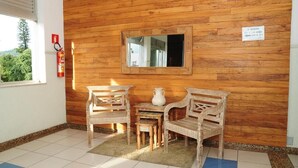Quarto com paredes de painel de madeira, um extintor de incêndio, um espelho e uma placa indicando o número do quarto 101.