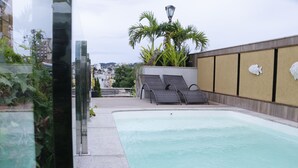 Uma área de piscina no terraço com espreguiçadeiras, um candeeiro e painel decorativo com desenhos de peixes.