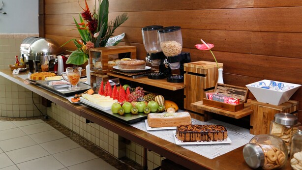 Um buffet com diversas opções de comida, incluindo frutas, doces e um espaço para café.