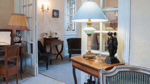 Quarto com uma escrivaninha de madeira, uma cadeira, um abajur e uma estátua.