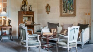 Uma sala de estar clássica com móveis antigos, um candelabro e um quadro na parede.