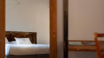 Quarto com cama, cabeceira de madeira e luminária fixada na parede.