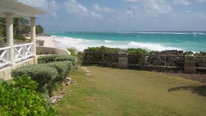 Vista costeira com praia, ondas do oceano e céu claro.