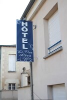 Placa de hotel com o nome 'HOTEL Le Clos Albert' fixada em um poste.