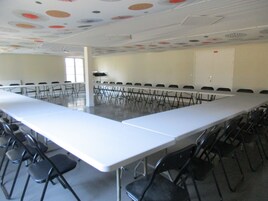 Uma sala de conferências com uma mesa comprida e cadeiras, um quadro branco e uma porta.