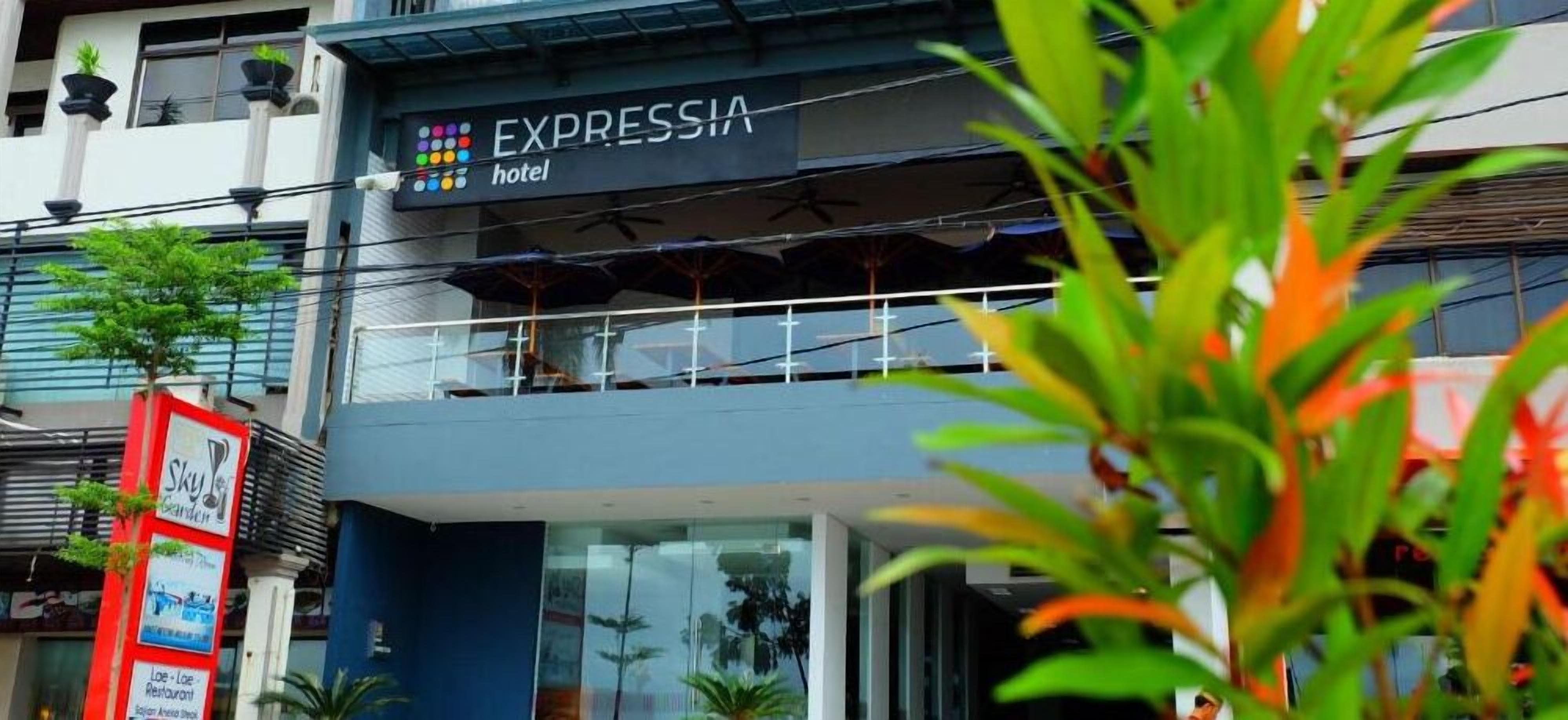 Um hotel chamado EXPRESSIA com fachada moderna, varandas e um restaurante com placa visível.