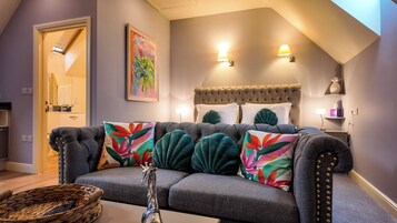 Uma sala de estar aconchegante com um sofá cinza, almofadas coloridas, uma escultura de girafa e um quadro na parede.