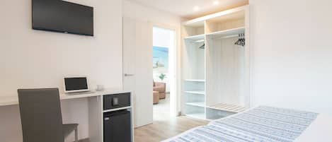 Quarto de hotel moderno com escrivaninha, laptop e cama com colcha estampada.