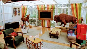 Uma sala de estar acolhedora com uma televisão grande, decoração rústica e vista para a floresta.