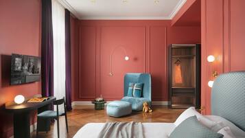 Quarto com cama, escrivaninha, cadeira, poltrona azul e luminária pendente.