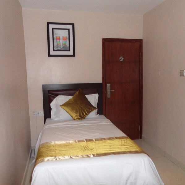 Quarto de hotel com cama, porta e quadro na parede.