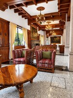 Um quarto espaçoso com teto de madeira, uma grande mesa redonda e sofás estampados.