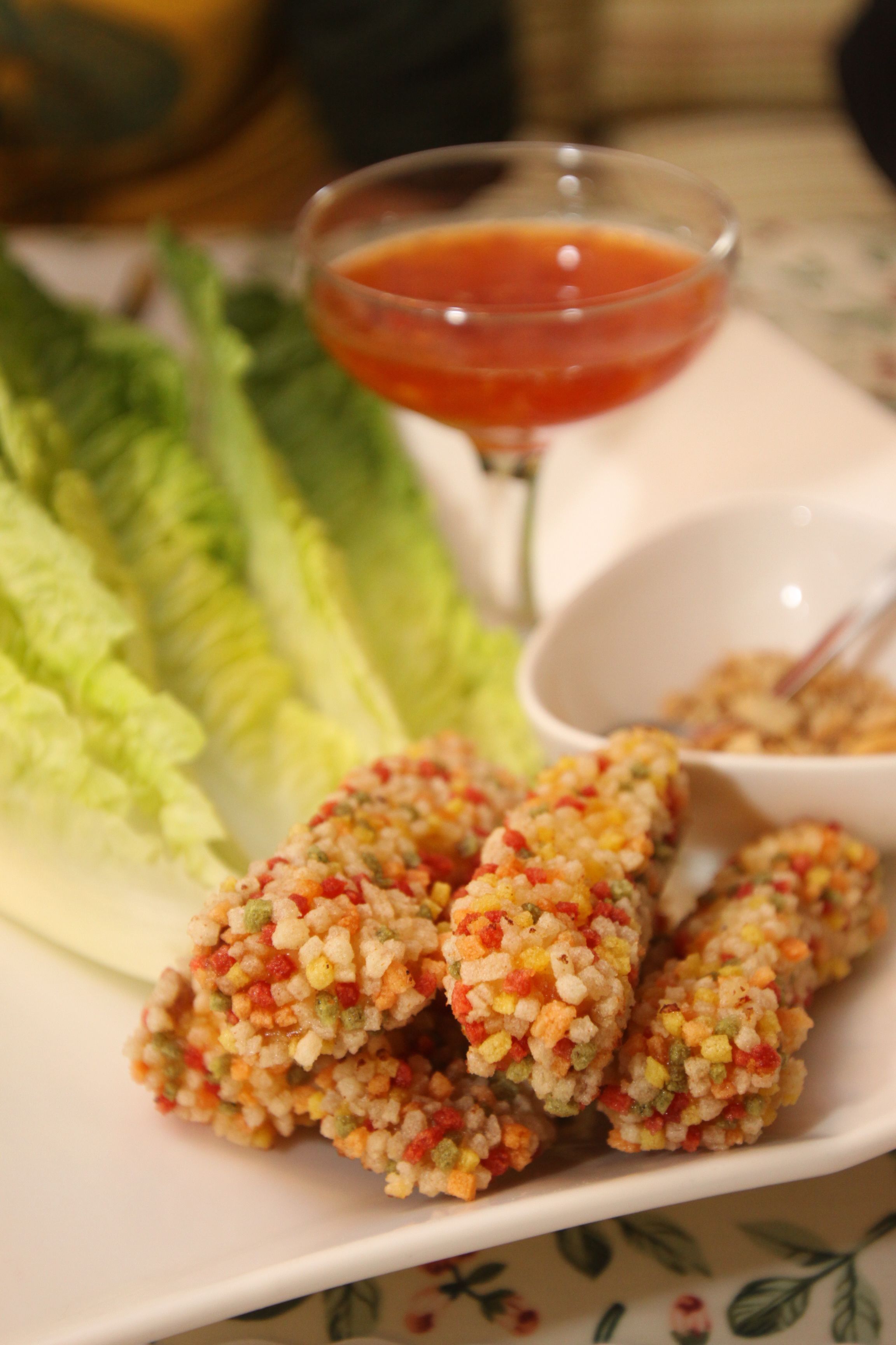Um prato com petiscos de arroz, um copo com molho vermelho e uma pequena tigela com molho extra.