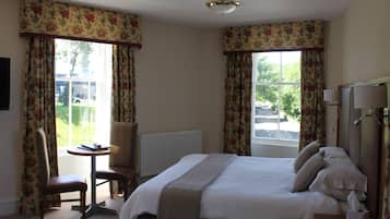 Quarto de hotel com uma cama, uma cadeira, uma mesa e uma janela com cortinas.