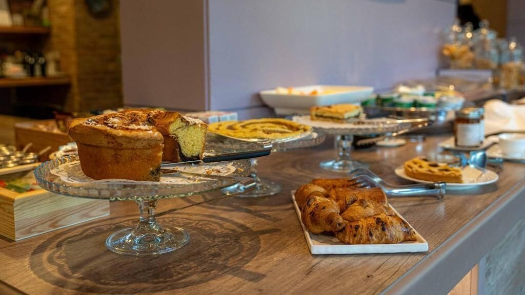 Um buffet com diversos produtos de panificação, incluindo um muffin, um bolo e doces.