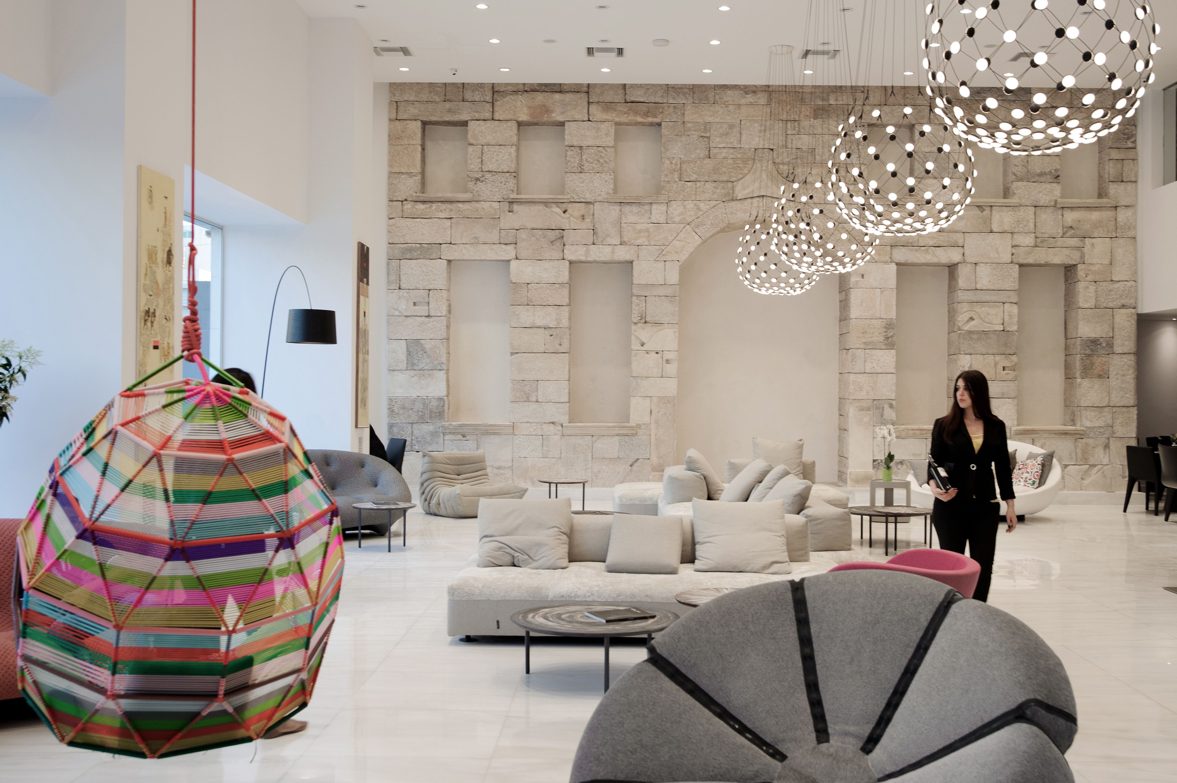 Um hall amplo com parede de pedra, móveis modernos e uma grande luminária pendente esférica.