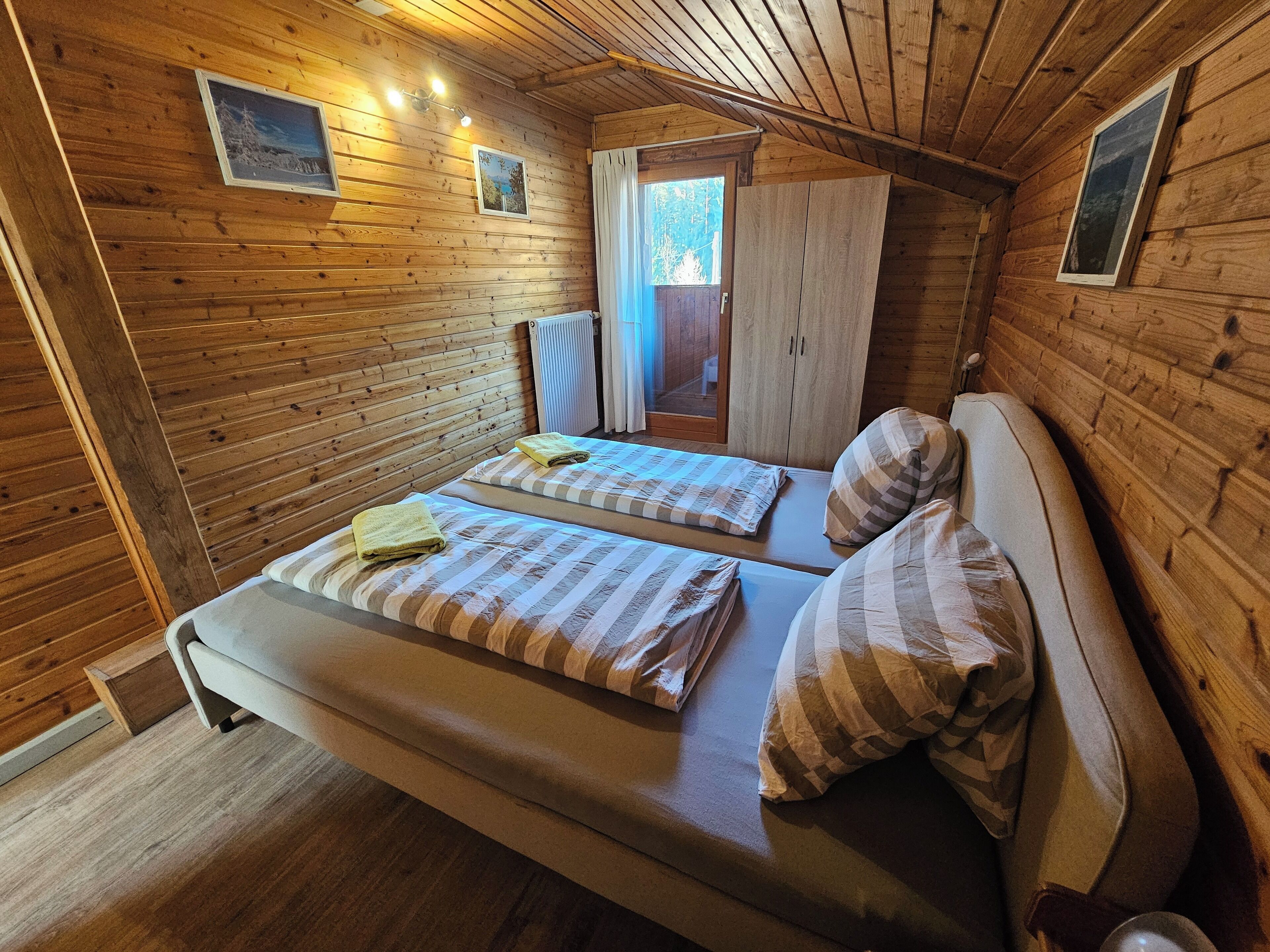 Quarto de cabana de madeira com duas camas, teto de madeira e uma janela.