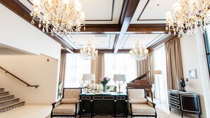Um quarto espaçoso com um piano de cauda, uma mesa de jantar com cadeiras e um candelabro.