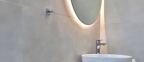 Casa de banho moderna com sanita, lavatório e espelho.