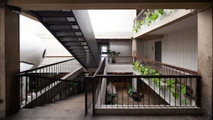 Um interior com vários níveis, com escada, corrimãos e plantas em vasos.