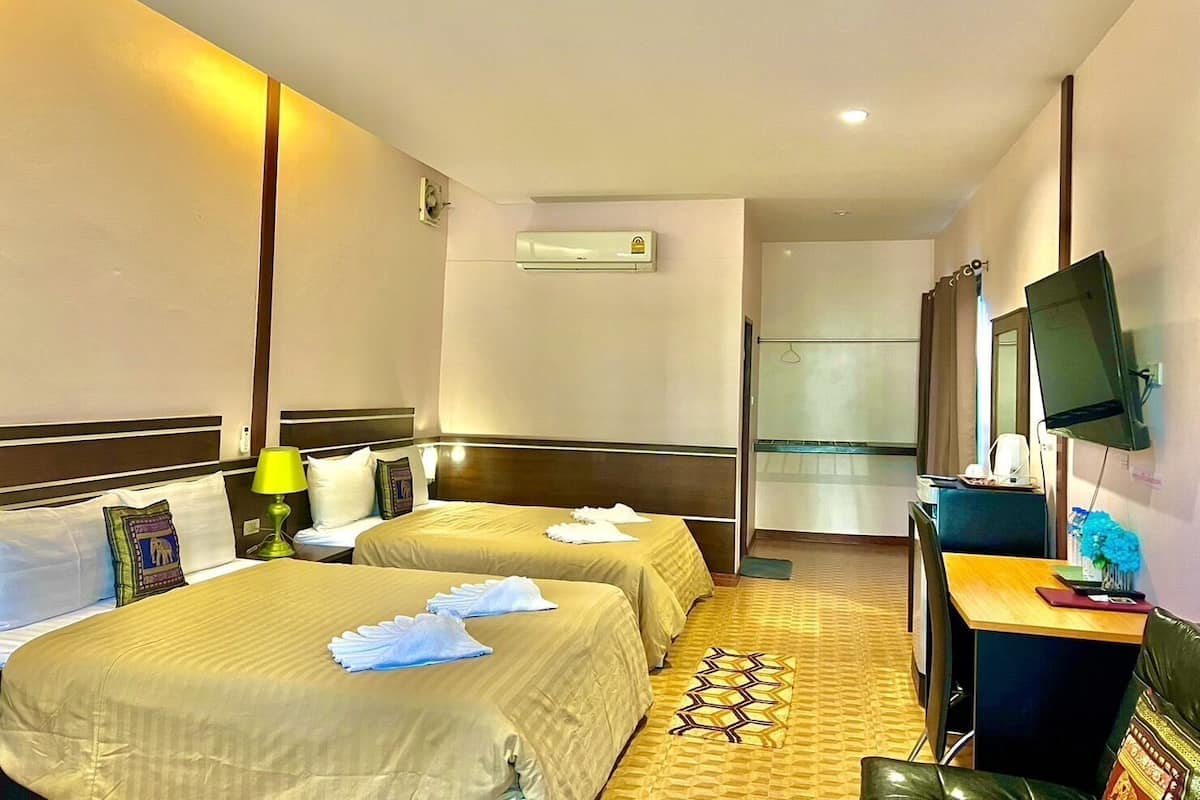 Quarto de hotel com duas camas, uma mesa de trabalho, televisão, ar condicionado e chuveiro.