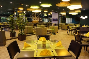 Um restaurante com várias mesas, cadeiras e plantas em vasos.