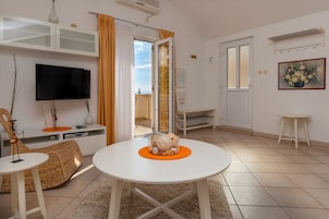 Apartamento superior, 2 quartos, sacada, vista para o mar | Área de estar | TV de tela plana