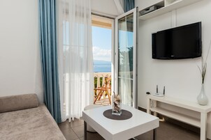 Apartamento superior, 1 quarto, sacada, vista para o mar | Área de estar | TV de tela plana