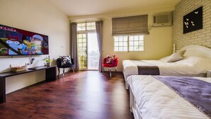 Quarto de hotel com duas camas, uma televisão na parede esquerda, uma cadeira vermelha e uma janela com cortinas.