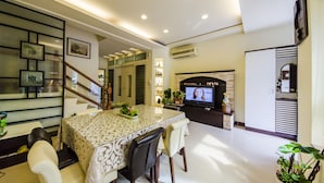 Uma sala de jantar moderna com uma mesa de vidro, duas cadeiras e uma televisão de tela plana.