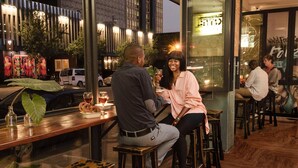 Um restaurante com área de bar, piso de madeira e vista para a rua.
