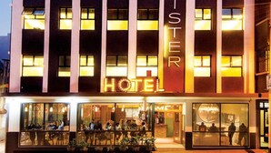 Um hotel com fachada moderna, vários andares e uma placa iluminada em destaque.