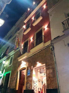 Fachada de hotel com uma loja boutique no andar térreo, entrada visível e uma placa indicando hotel.