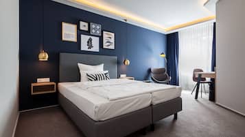 Quarto de hotel moderno com uma cama grande, mesas de cabeceira, uma escrivaninha e uma cadeira.