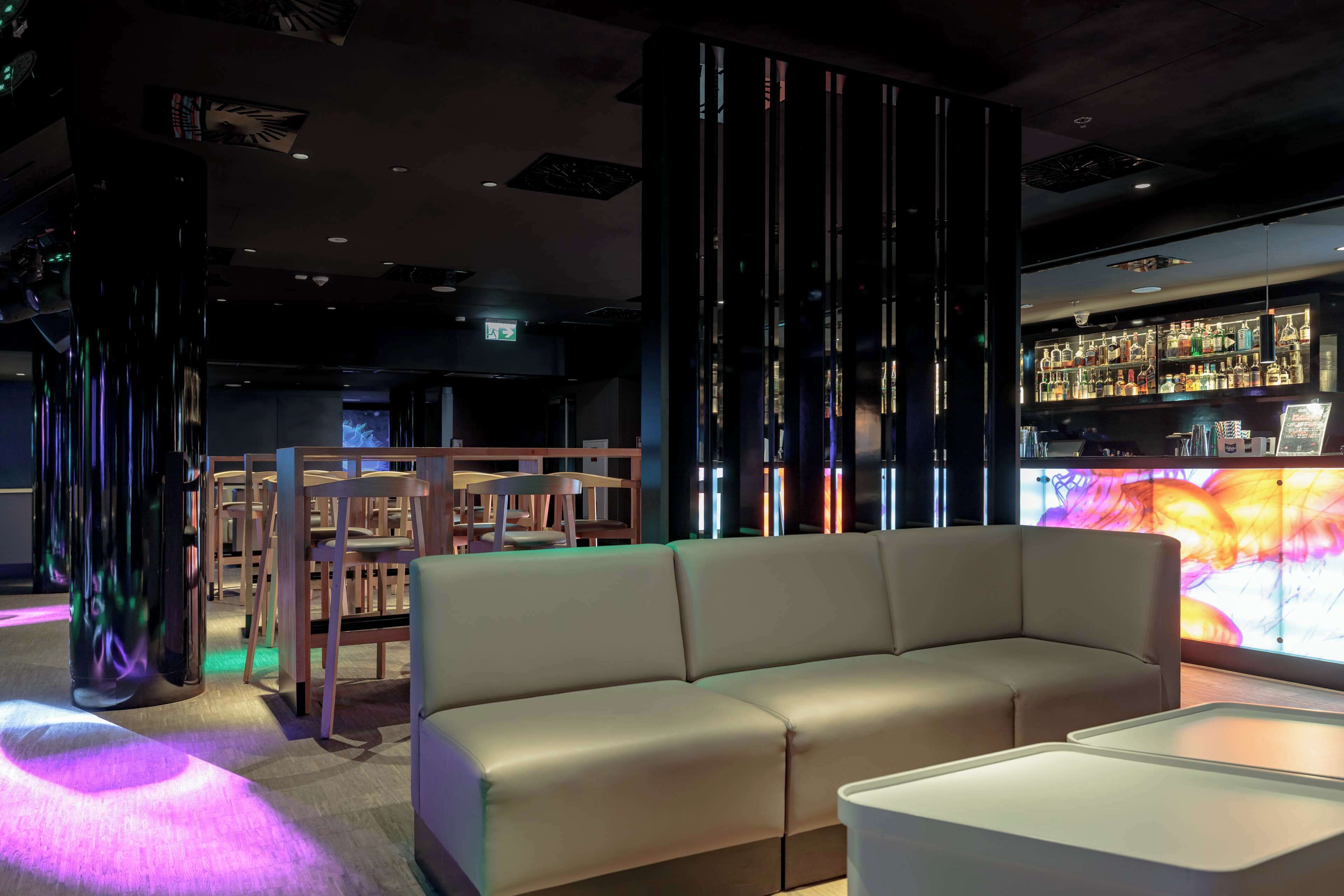 Espaço lounge moderno com um sofá e um bar com uma exposição colorida.