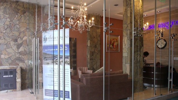 Um lobby com parede de pedra, um candelabro, um sofá e um balcão de recepção.