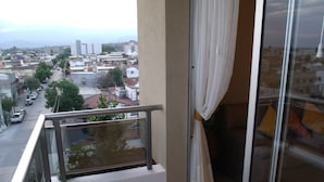 Uma varanda com vista para a cidade, uma porta de vidro e uma cortina.