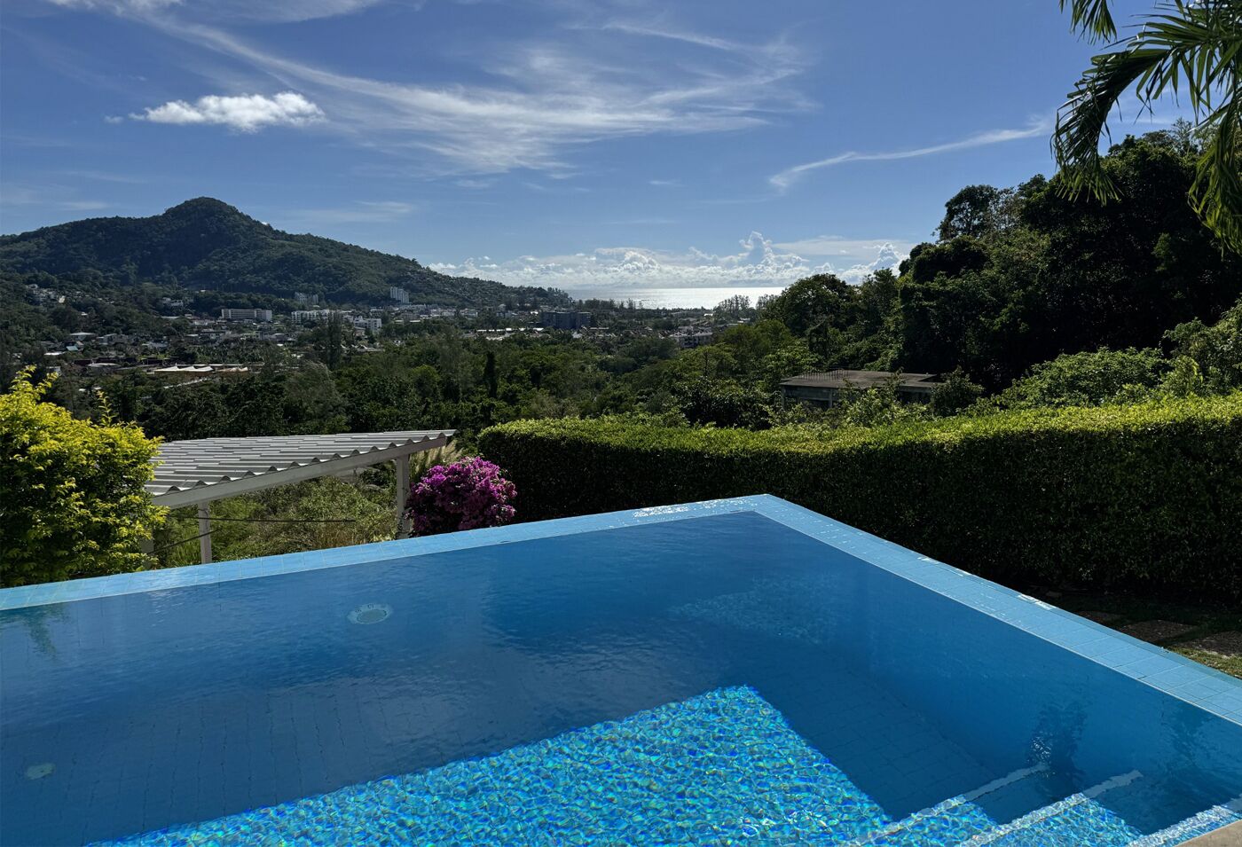 Piscina com vista clara para um horizonte urbano e montanhas ao fundo.