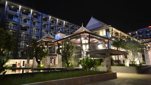 Um hotel moderno com várias varandas, piscina e áreas externas bem iluminadas.