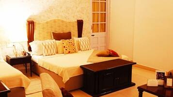 Quarto de hotel com cama, escrivaninha, cadeira e mesa pequena.