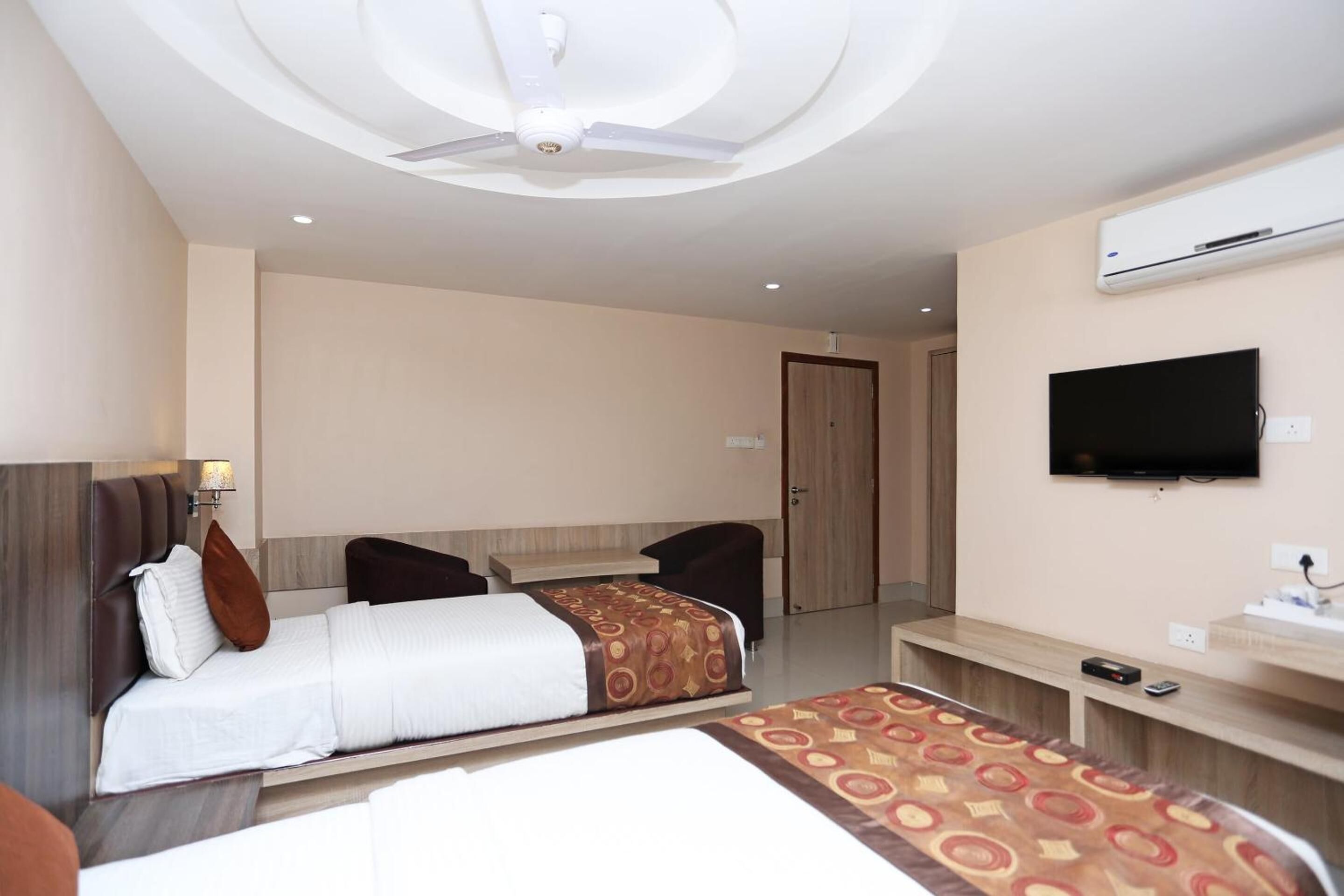 Quarto de hotel com uma cama, uma escrivaninha, uma cadeira, uma televisão e um ar condicionado.
